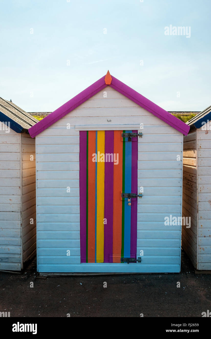 A beach hut in a row of huts brightens the shady position with a door ...
