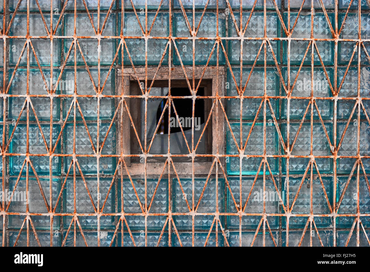 glass block of the old window covered with rusty grid for construction ...