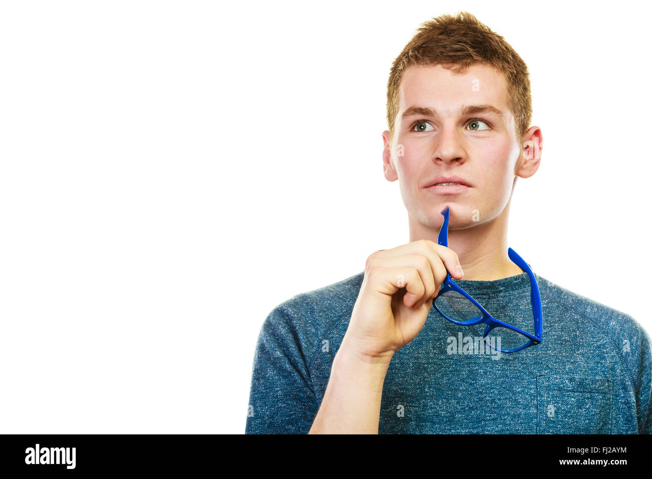 Young man holding blue glasses in hand thinking isolated on white ...