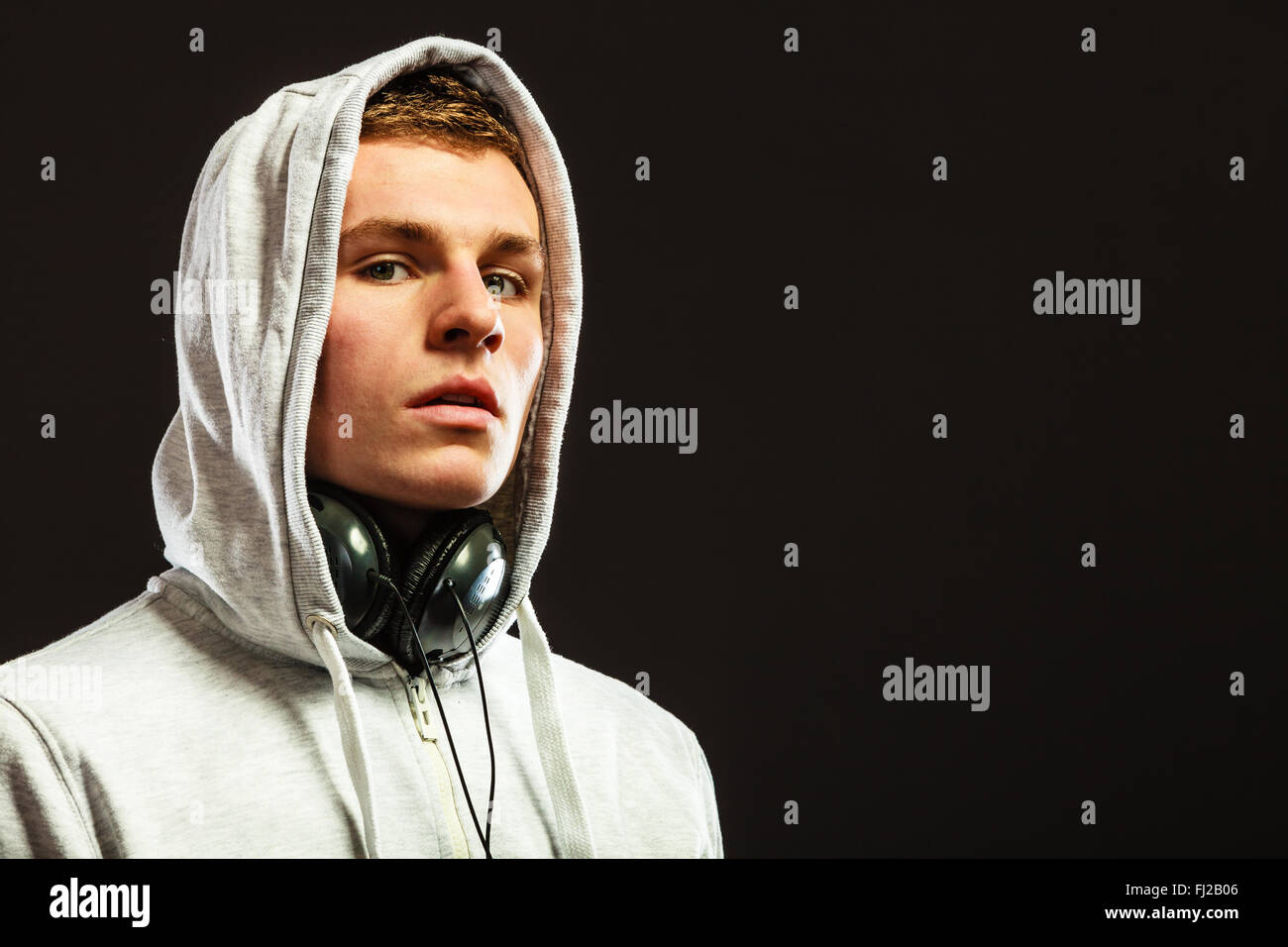 Headshot young handsome hooded man with headphones listening to music ...