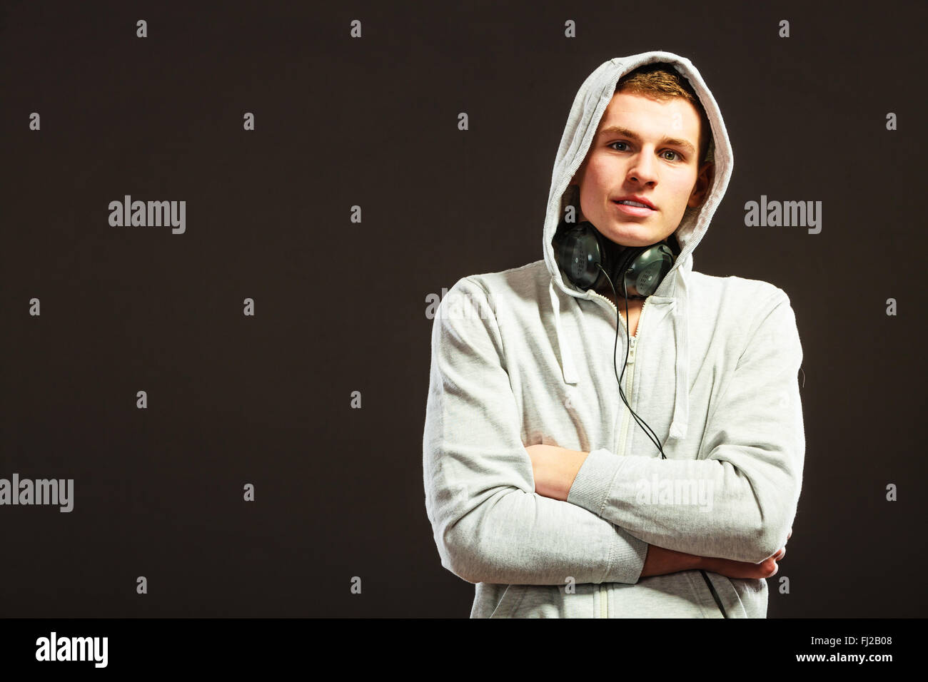 Headshot young handsome hooded man with headphones listening to music ...