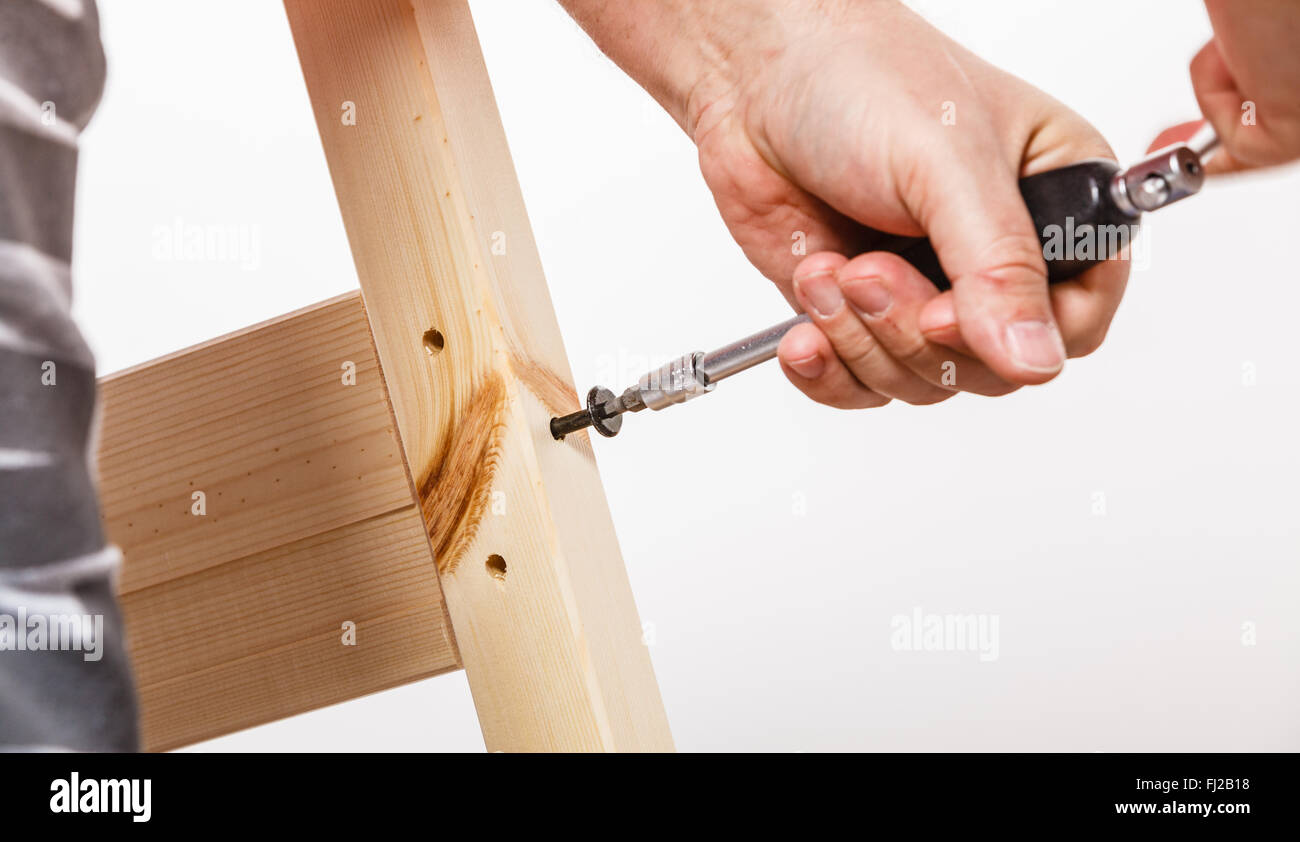 Human hand assembling wood furniture using screwdriver. DIY enthusiast ...