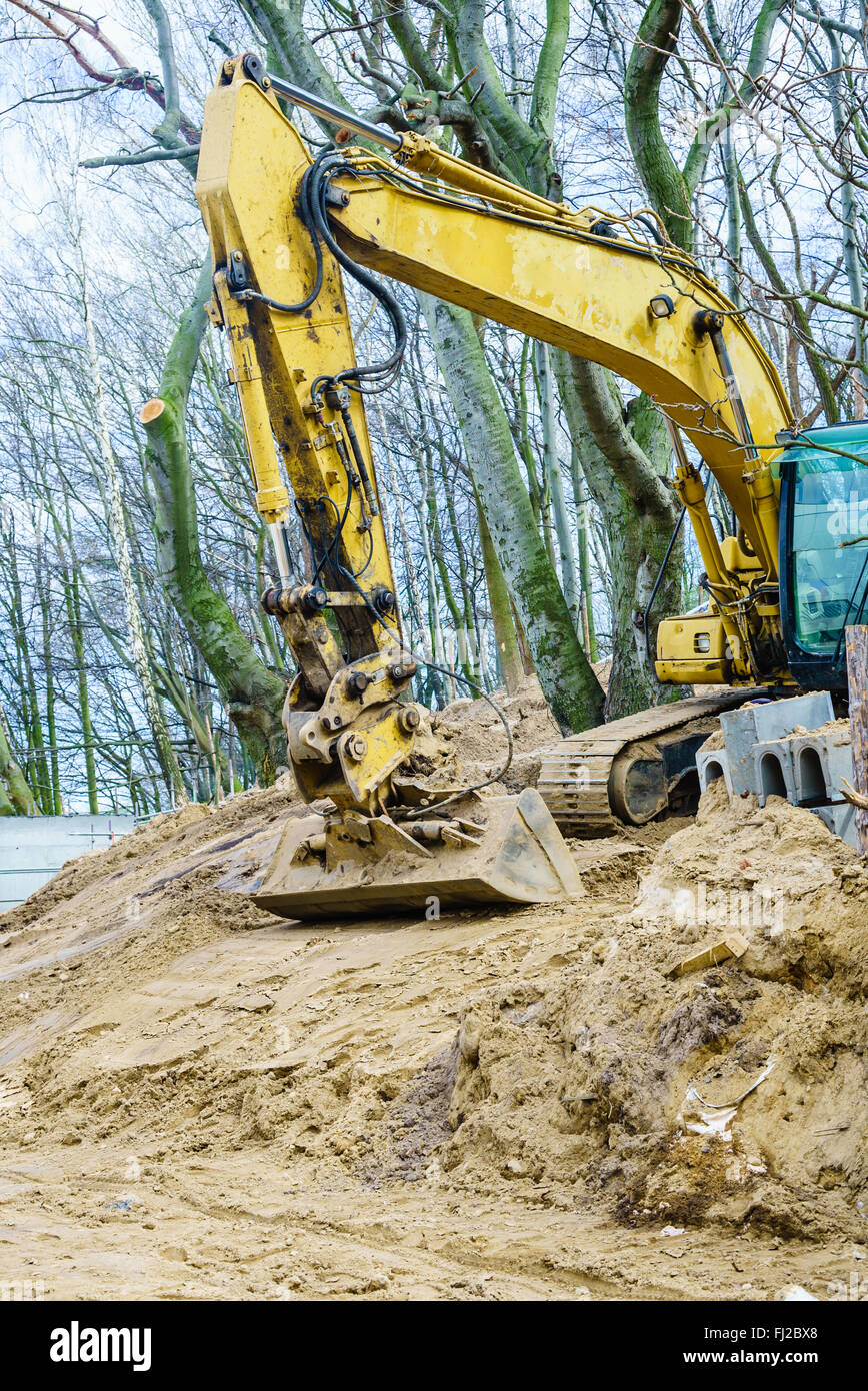 Yellow excavator dig digging trench on construction site in forest ...