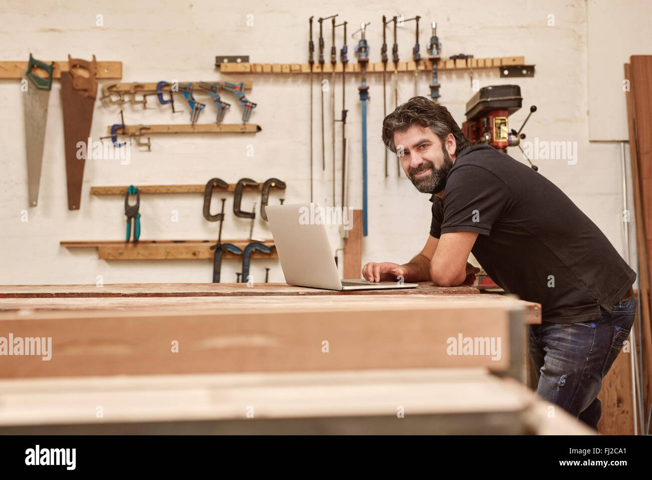 Woodwork artisan in his workshop studio with a laptop Stock Photo - Alamy