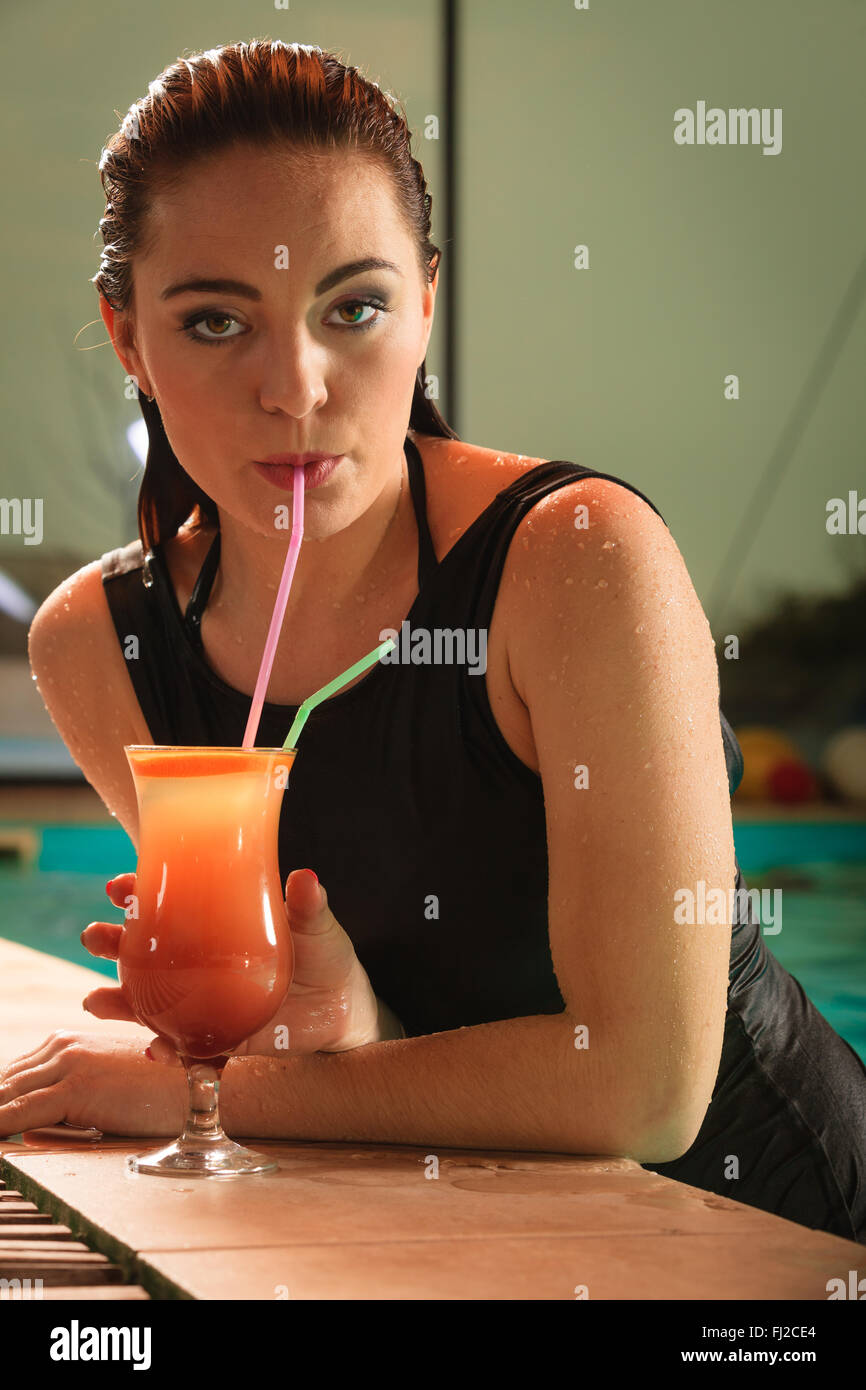 Woman in black dress relaxing at swimming pool edge poolside. Young ...
