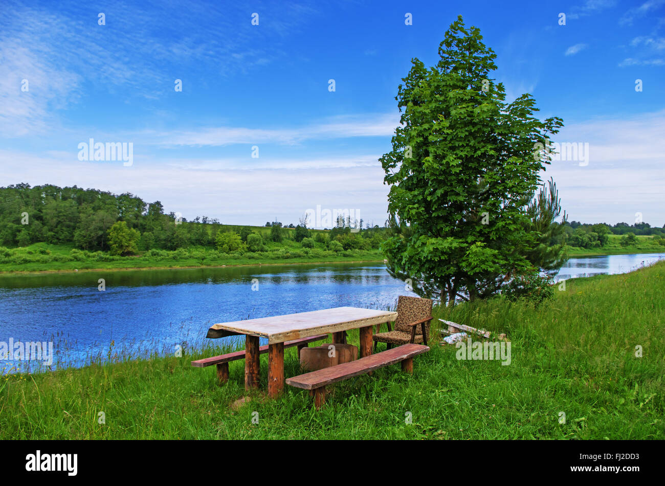 Village landscape. Table and benches by the river Stock Photo - Alamy