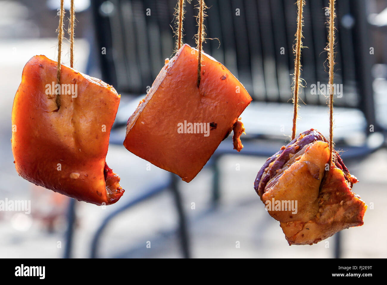 Three bacon hanging outside with backlight Stock Photo - Alamy