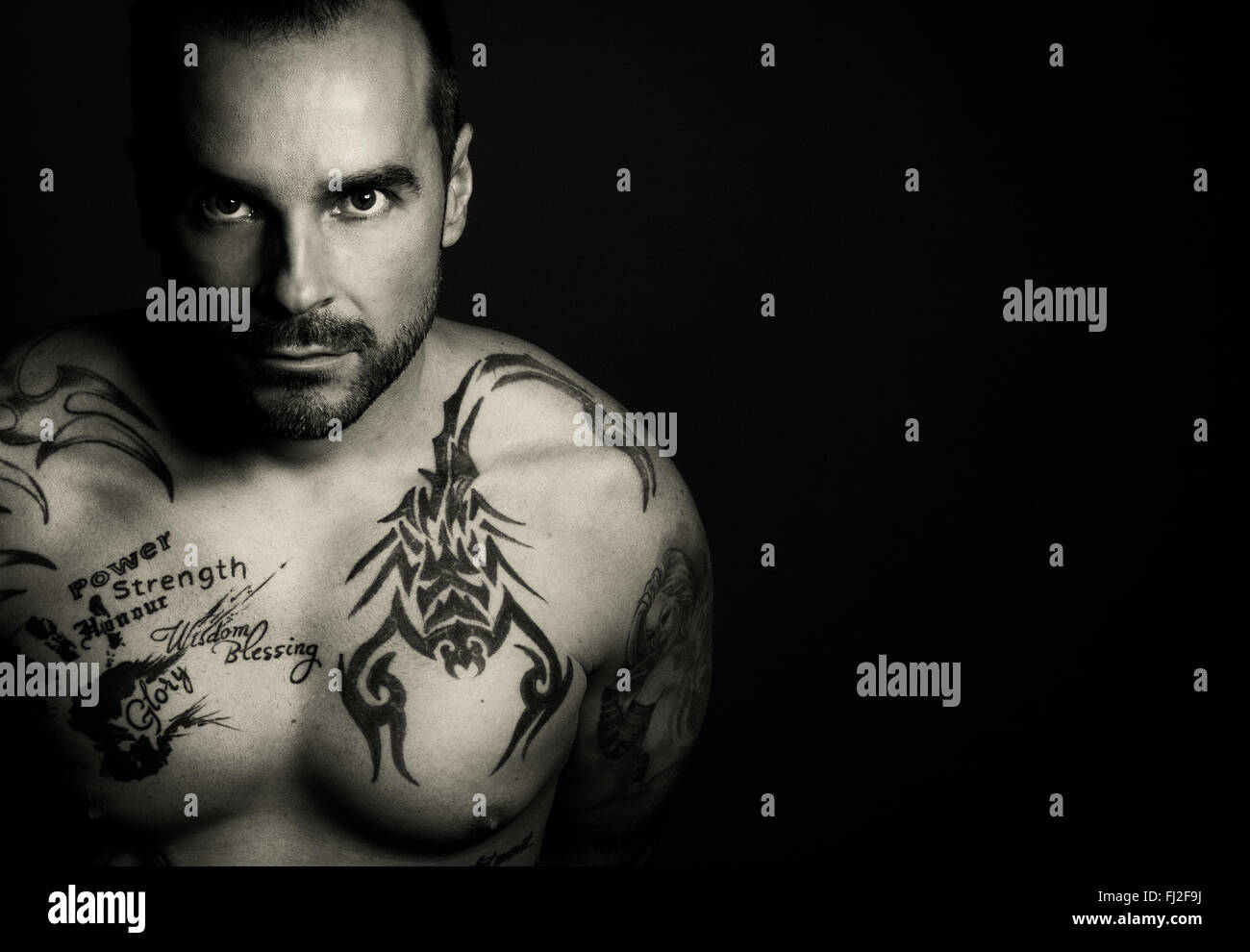 shirtless man with beard and scorpion tattoo staring down with ...