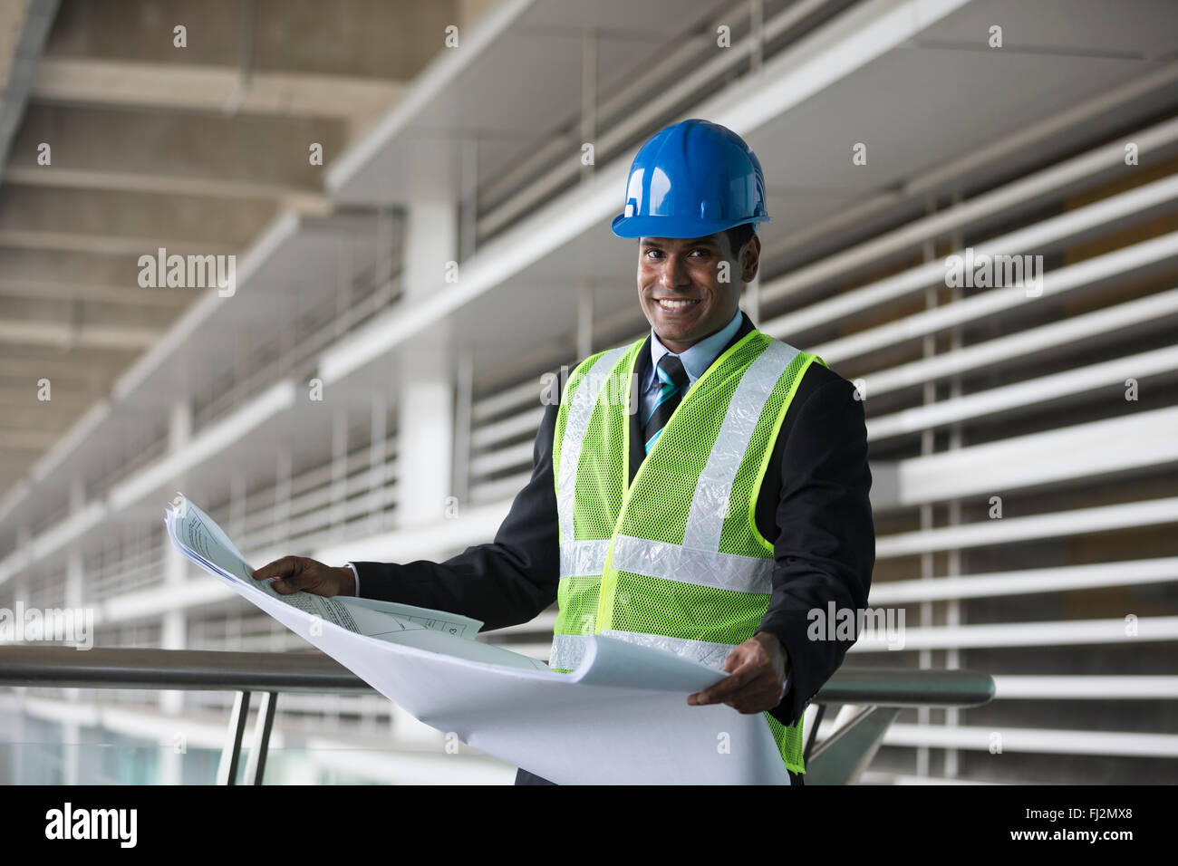 Portrait of a male Indian industrial engineer at work holding technical ...