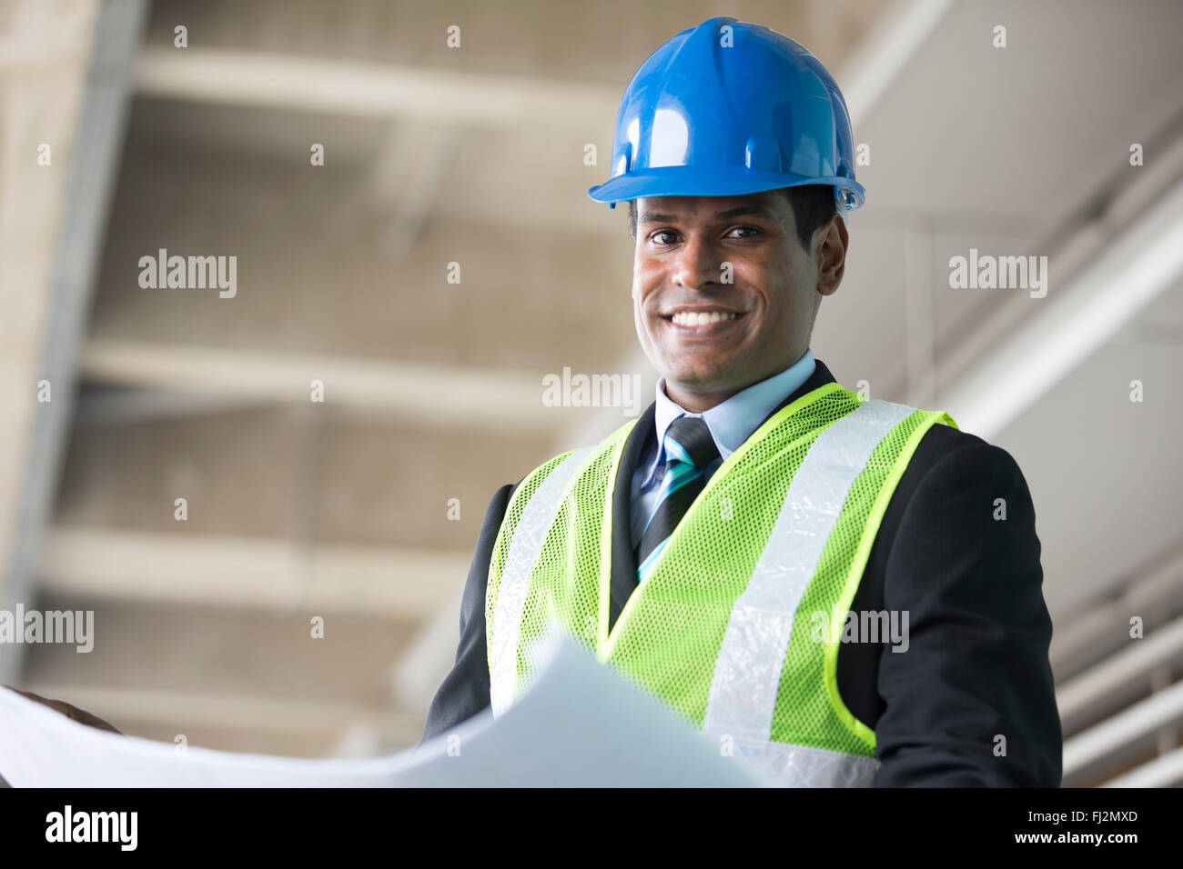 Portrait of a male Indian industrial engineer at work holding technical ...