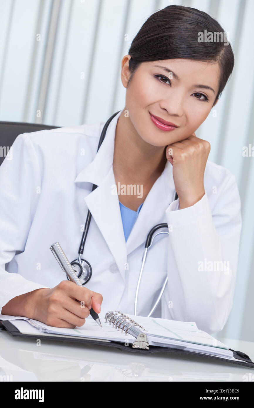 A Chinese Asian female medical doctor writing in a hospital office ...