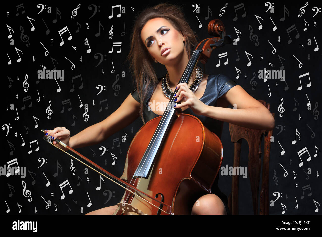 Pretty young female musician playing the cello Stock Photo - Alamy