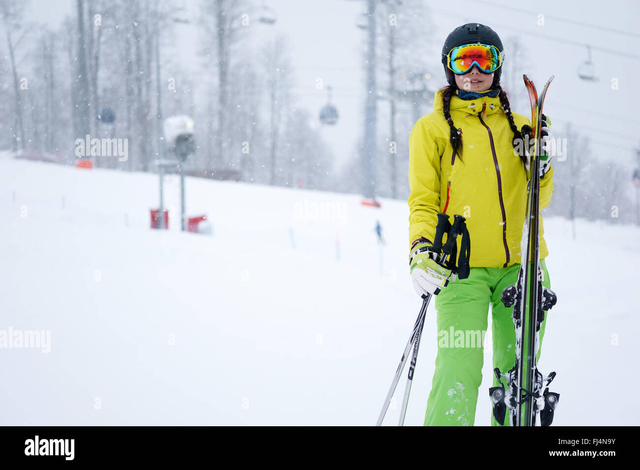 Female skier standing with skies in one hand on background beautiful ...
