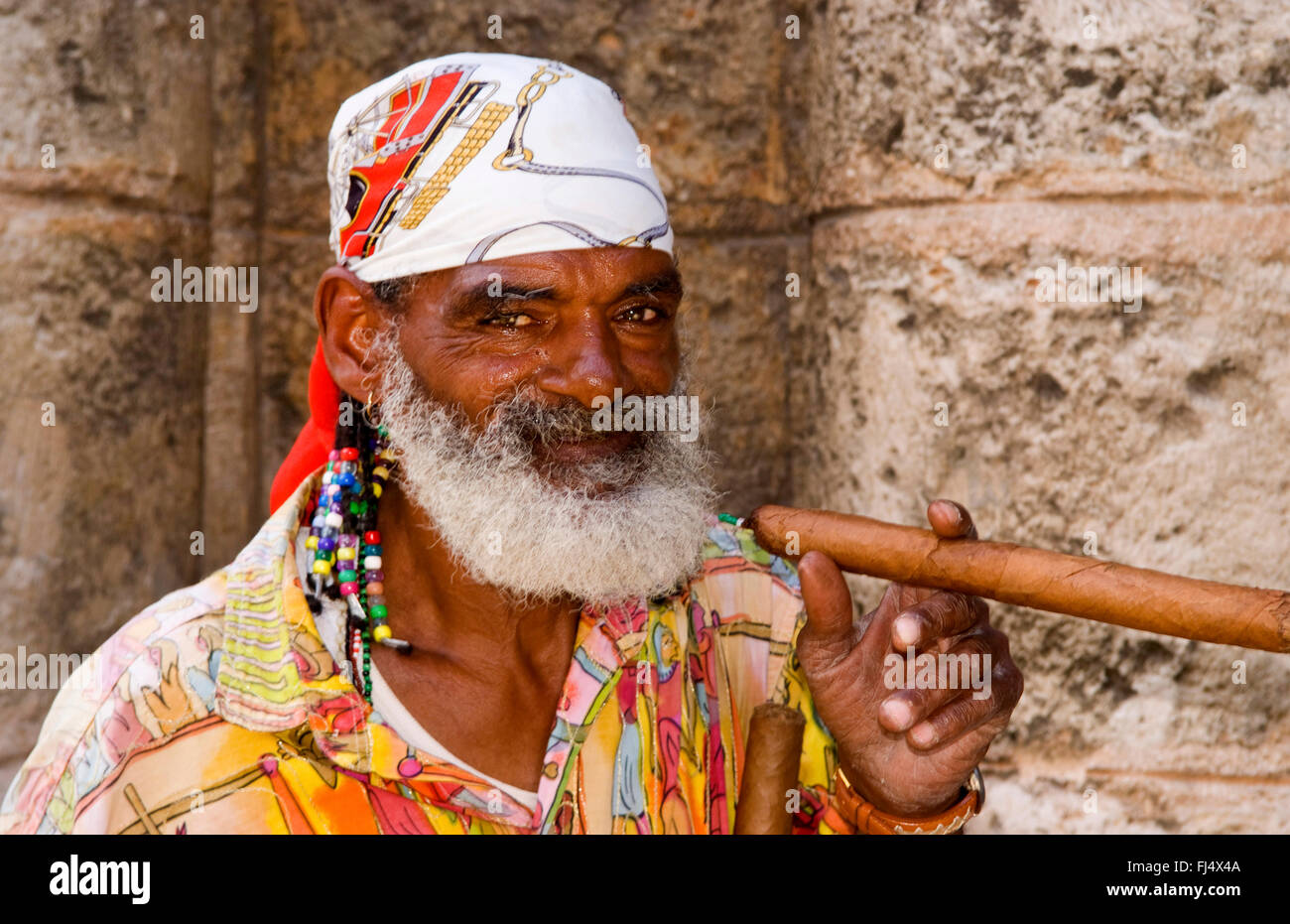 older Cuban with full beard and scarf smoking a long cigar, portrait ...