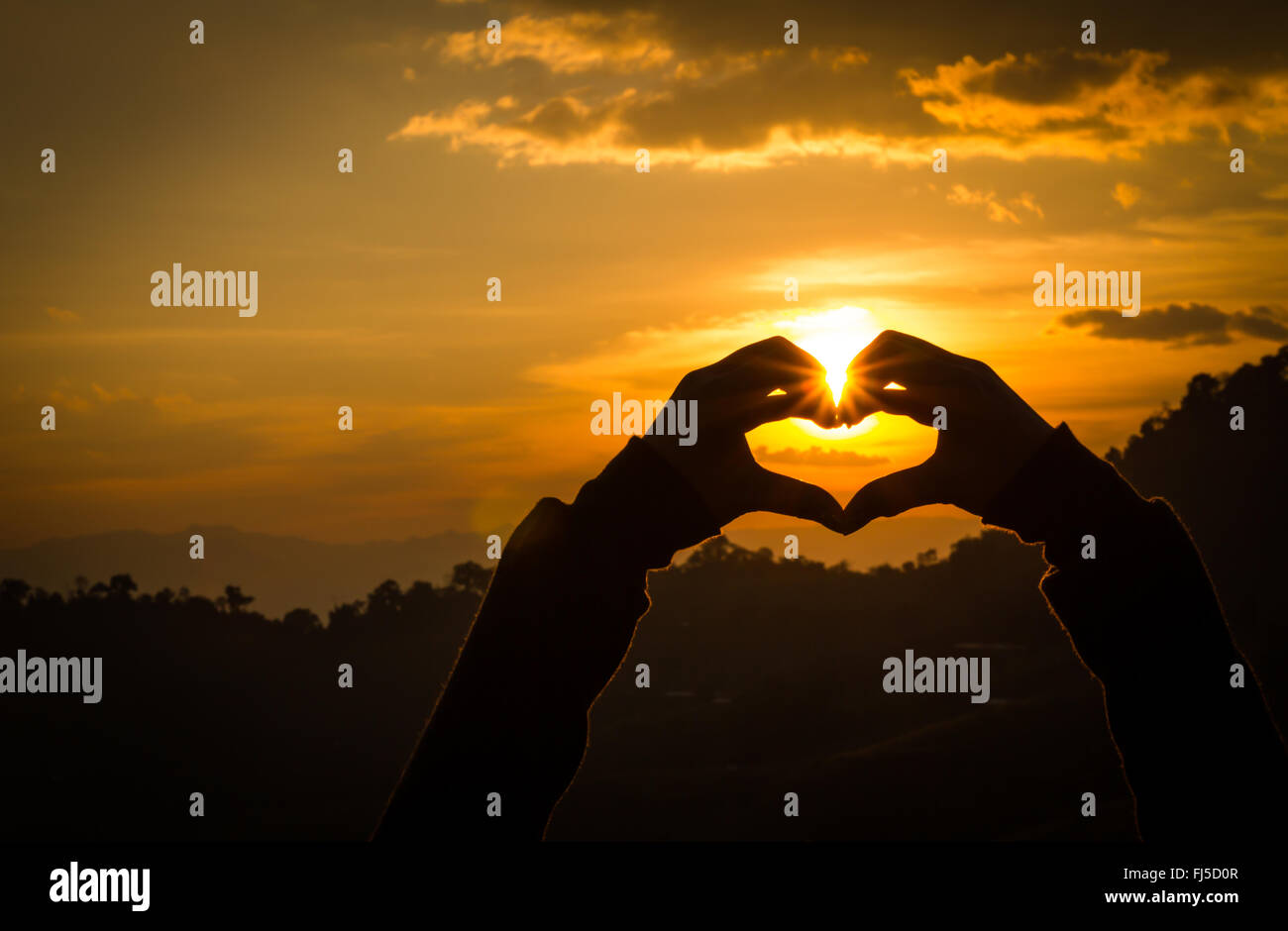 Silhouettes hand heart shaped with sun sets and the sky orange Stock ...