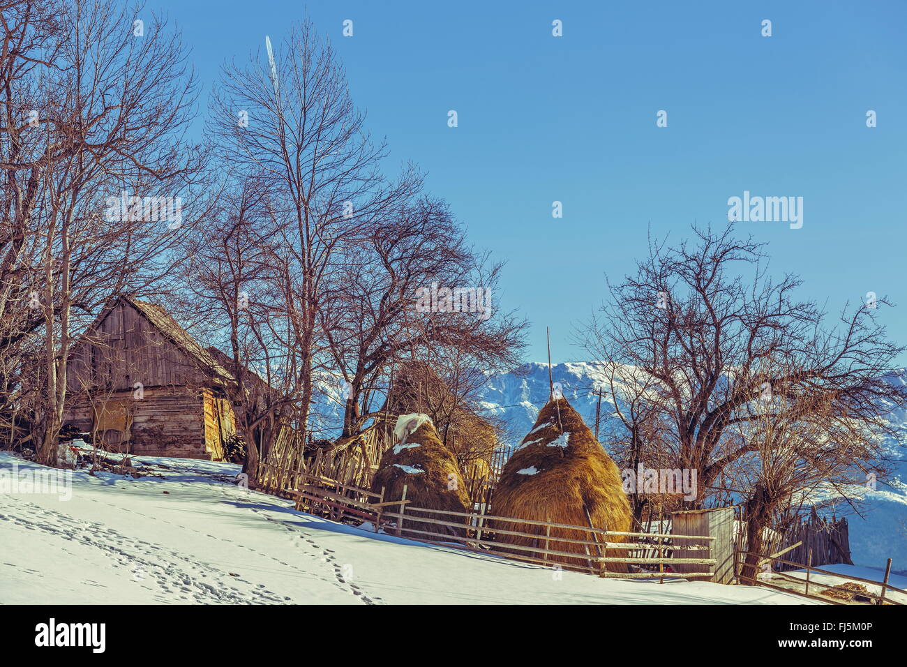 Rural scenery with ancient traditional Romanian farm on a winter sunny ...