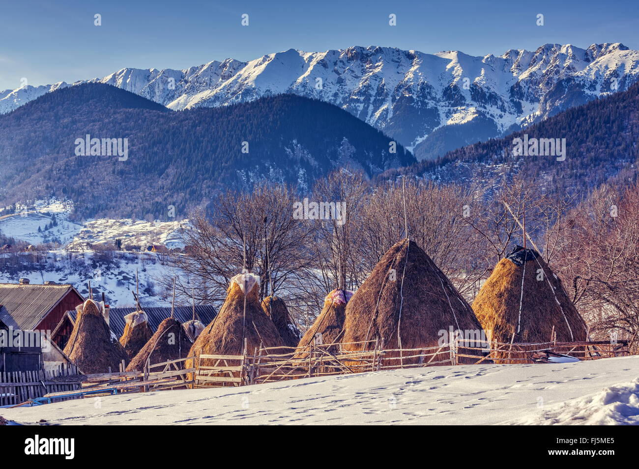 Winter rural landscape with traditional Romanian farm with sheep pen ...