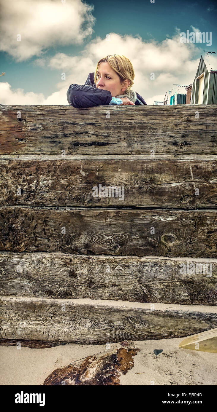 young woman resting her arms on wooden fence on the beach Stock Photo ...