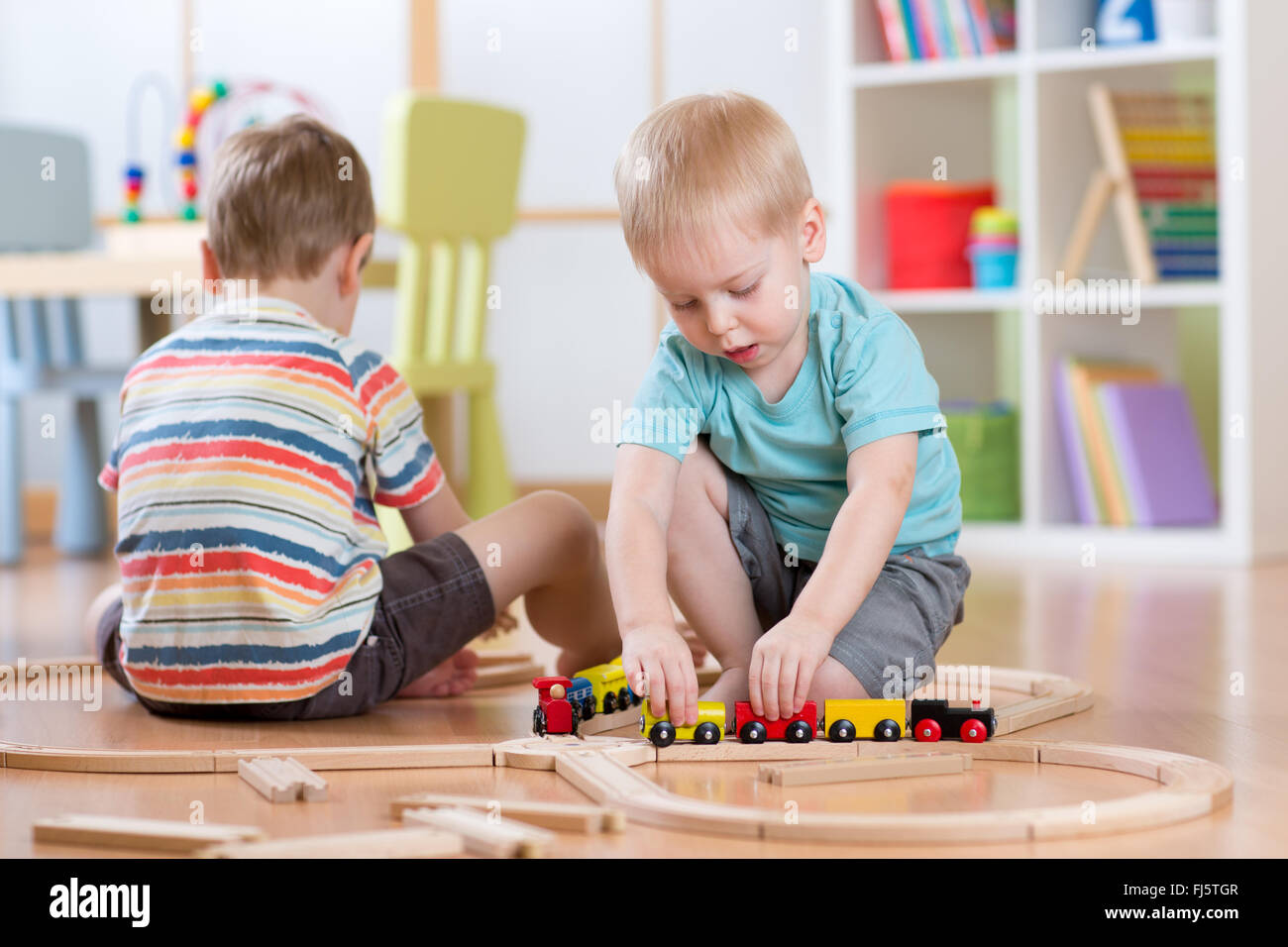 Children boys playing rail road toy in nursery Stock Photo - Alamy