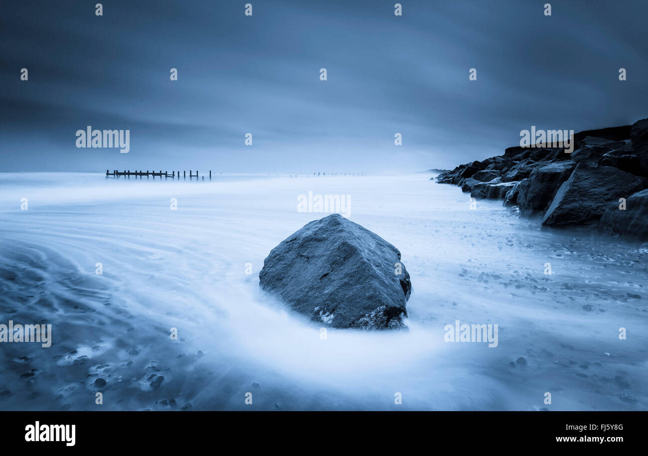 A single rock from the sea defenses surrounded by the rushing waves ...