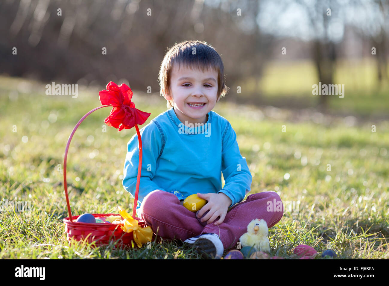 Adorable boy in the park, having fun with colored eggs for Easter ...