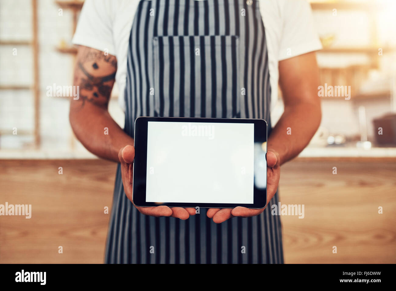 Close up shot of a man wearing an apron showing a digital tablet. Male ...