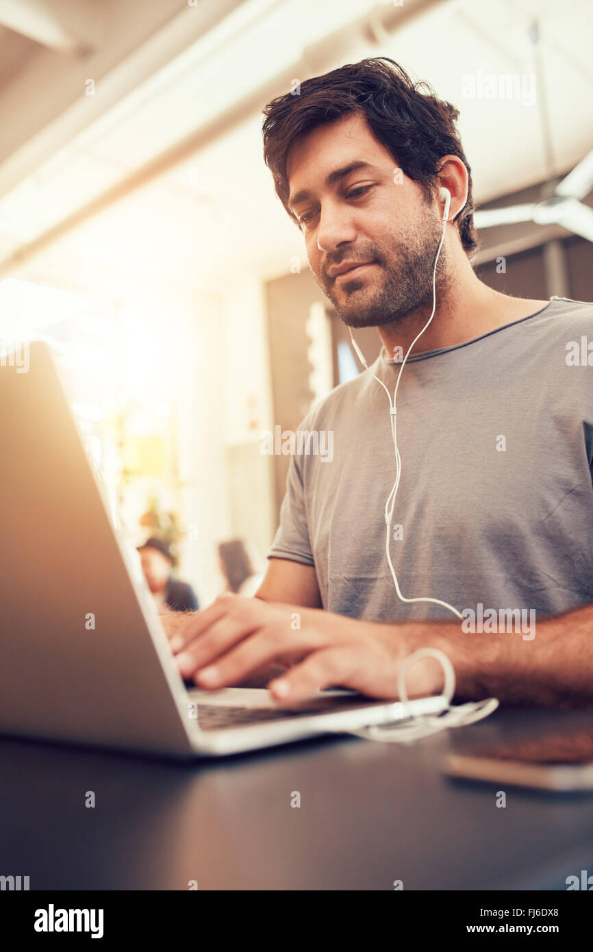 Portrait of young man looking busy working on laptop at a cafe ...