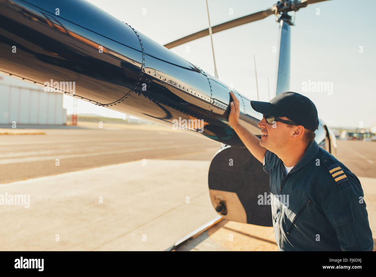 Male pilot checks the tail of helicopter before the flight. Mechanic ...