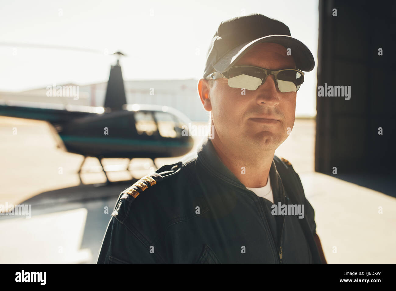 Close up portrait of professional pilot standing in airplane hangar ...
