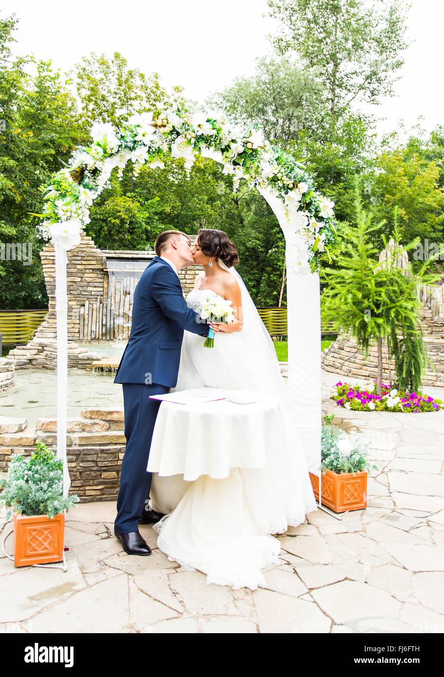 First kiss of newly married couple under wedding arch Stock Photo - Alamy