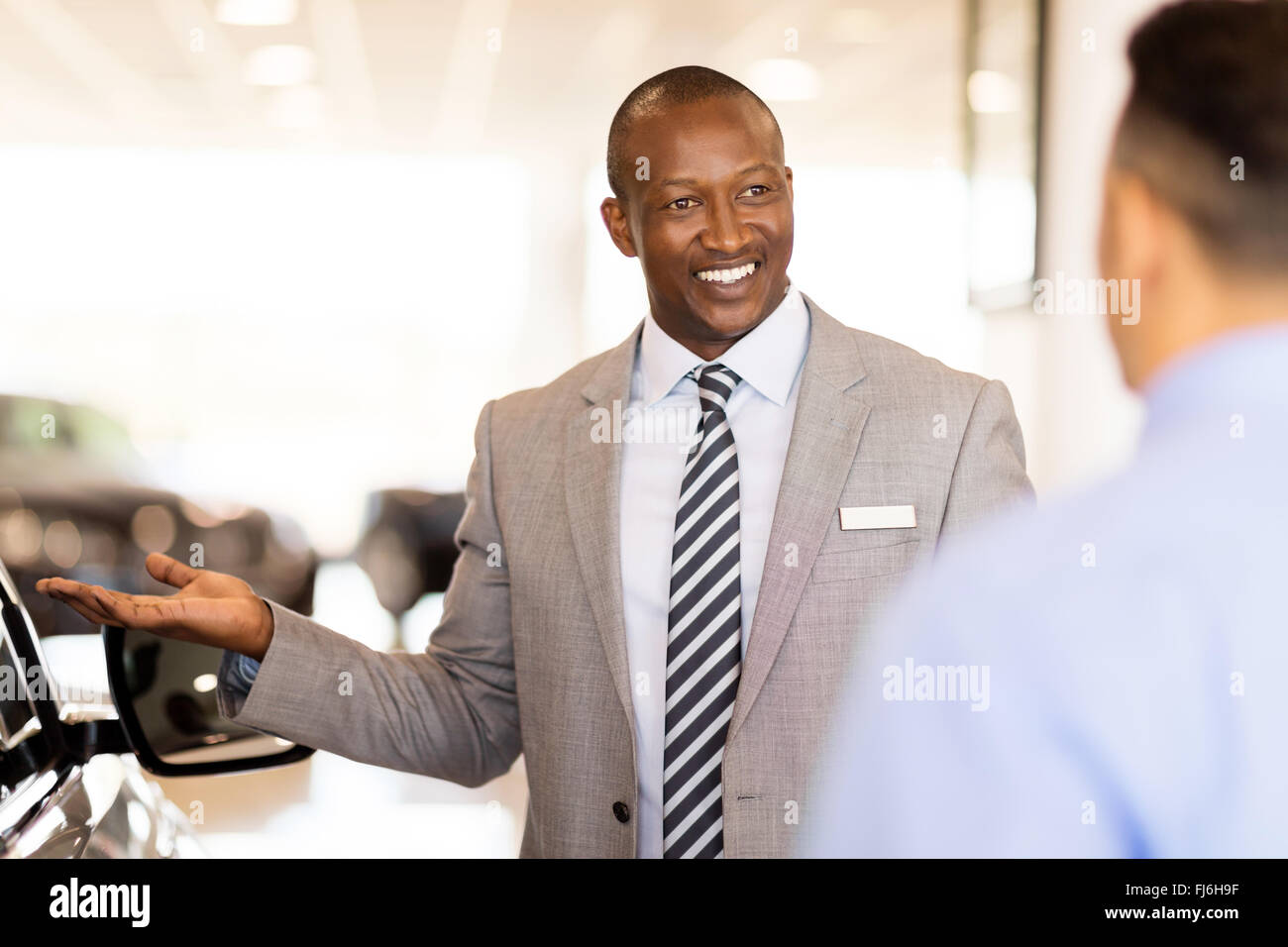 handsome African salesman presenting new car to clients Stock Photo - Alamy