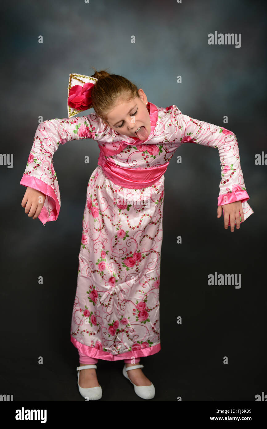 Adorable young girl dressed up as a Geisha against gray background ...