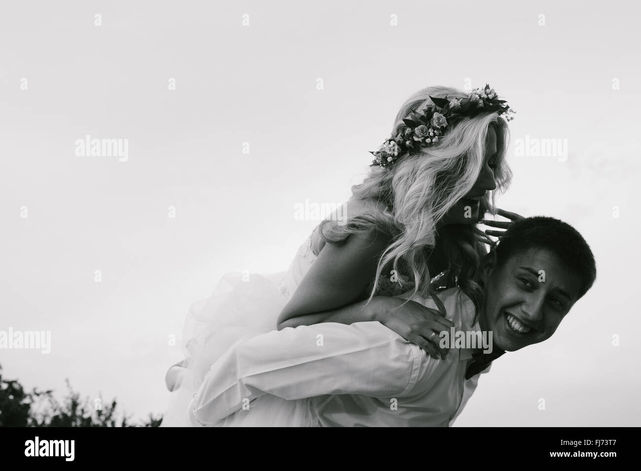 groom carries bride on his back outdoors Stock Photo - Alamy