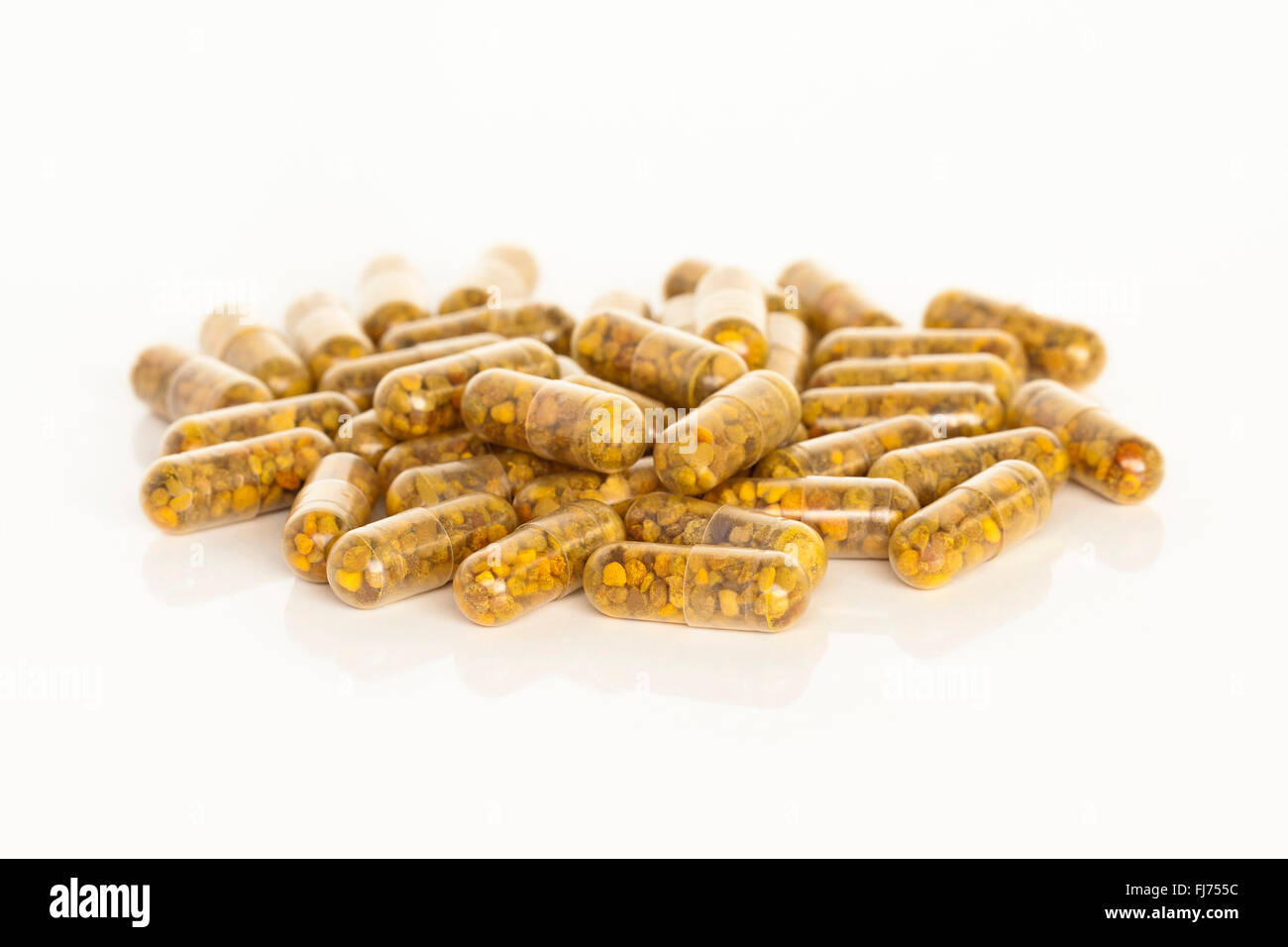 A pile of bee pollen supplement capsules isolated on a white background ...