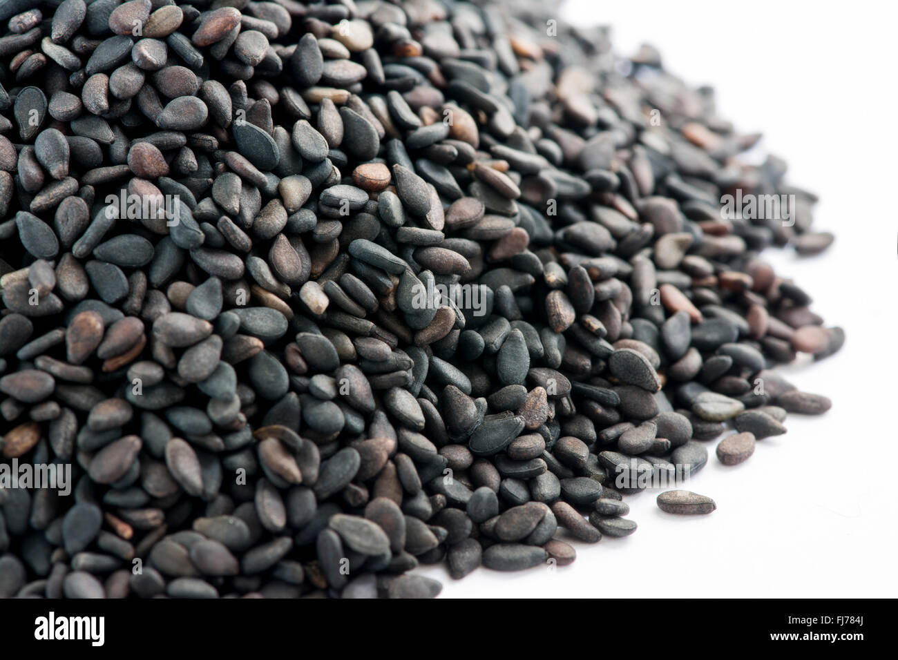 black sesame seeds with a narrow depth of field on a white background ...