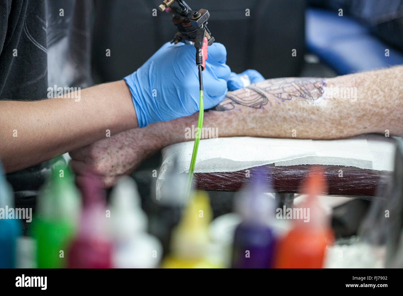 Ink bottles and tattoo artist inking a client with a bio-mechanical ...