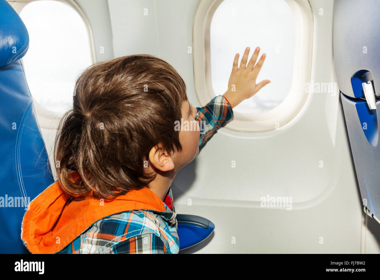 Little boy on airplane touch window with hand Stock Photo - Alamy