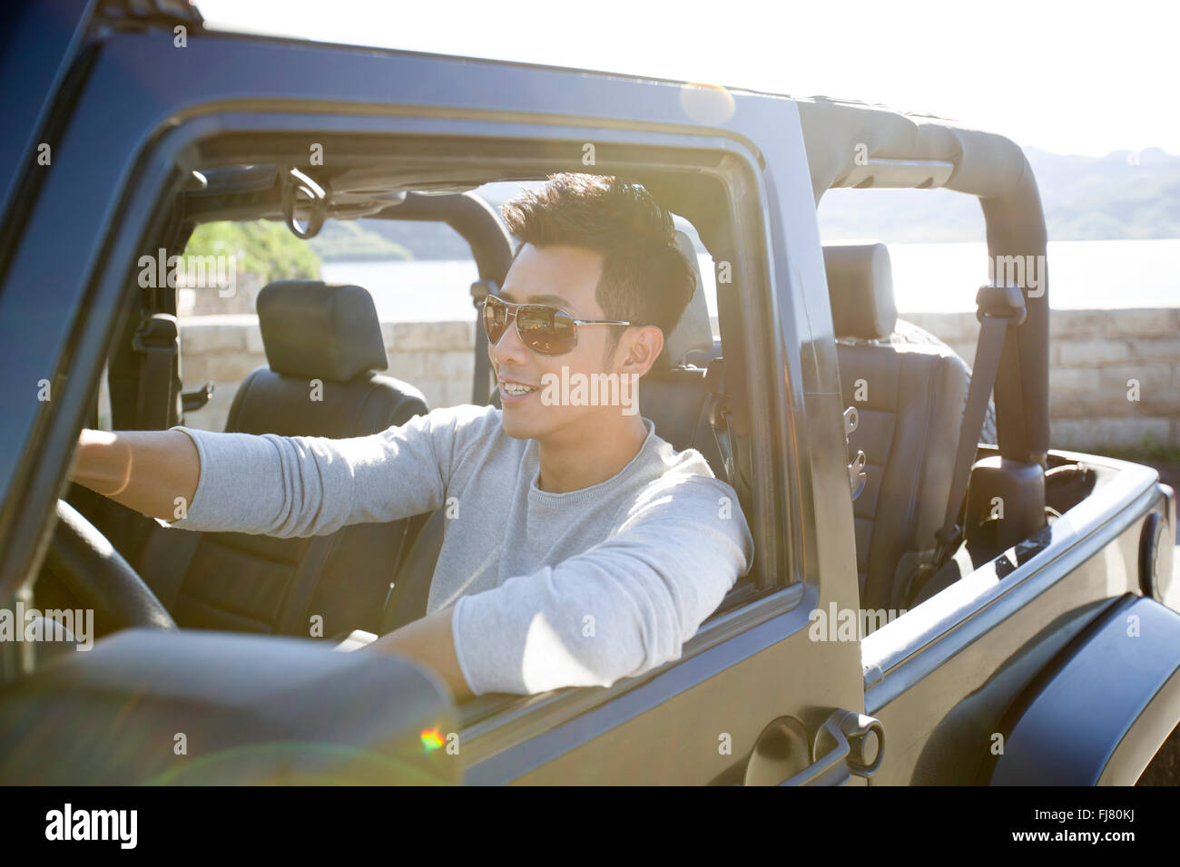 Happy young Chinese man driving a jeep Stock Photo - Alamy