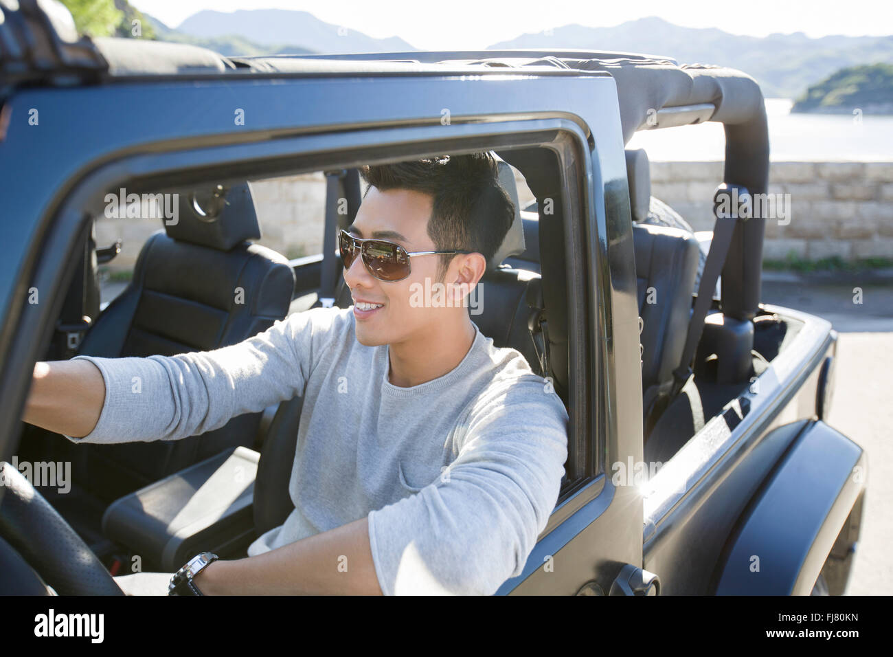 Happy young Chinese man driving a jeep Stock Photo - Alamy