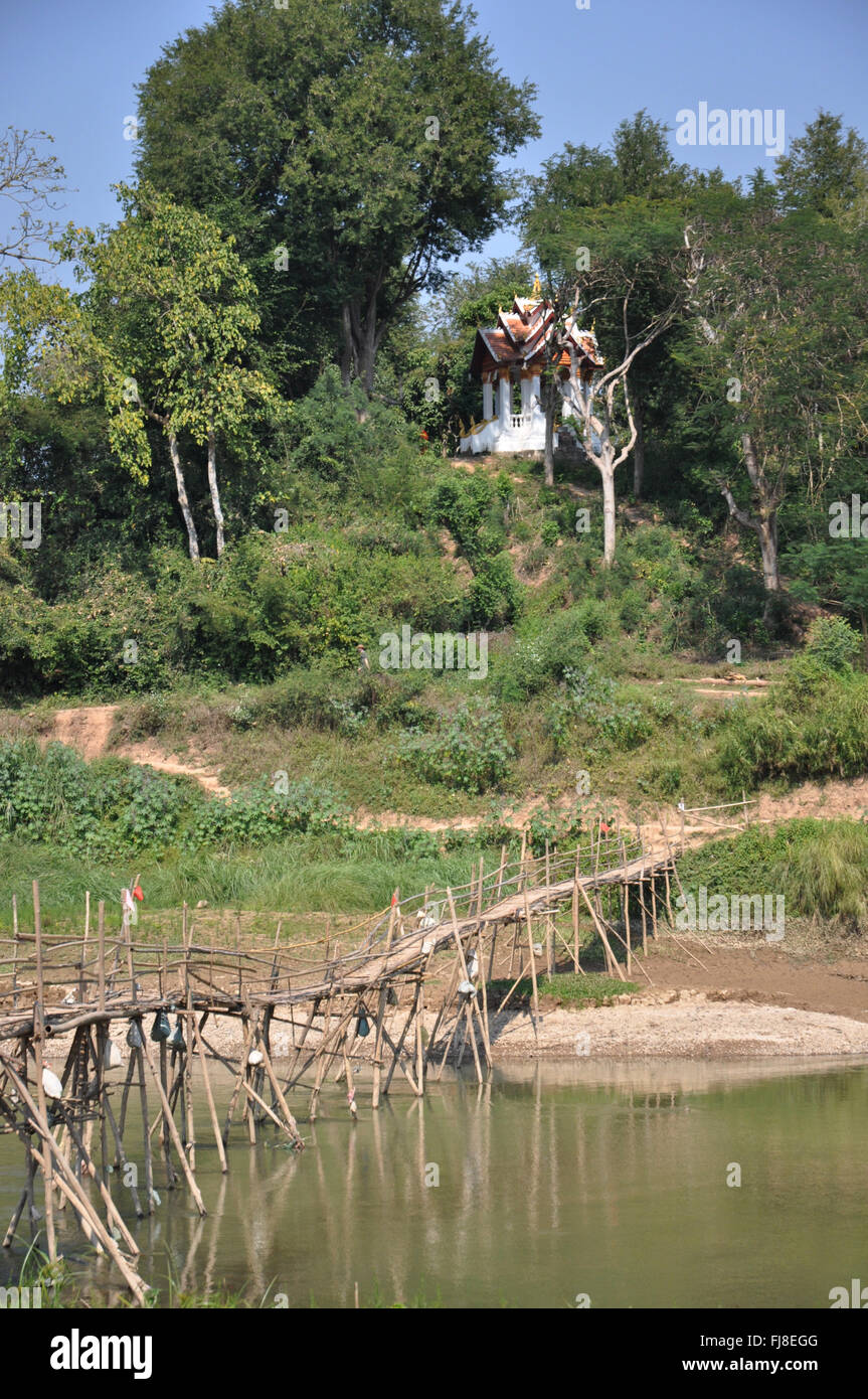 Bamboo bridge across the Nam Kham River, temple at the top of the hill ...