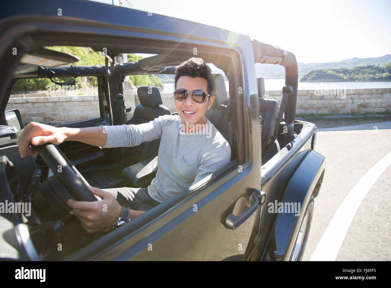 Happy young Chinese man driving a jeep Stock Photo - Alamy