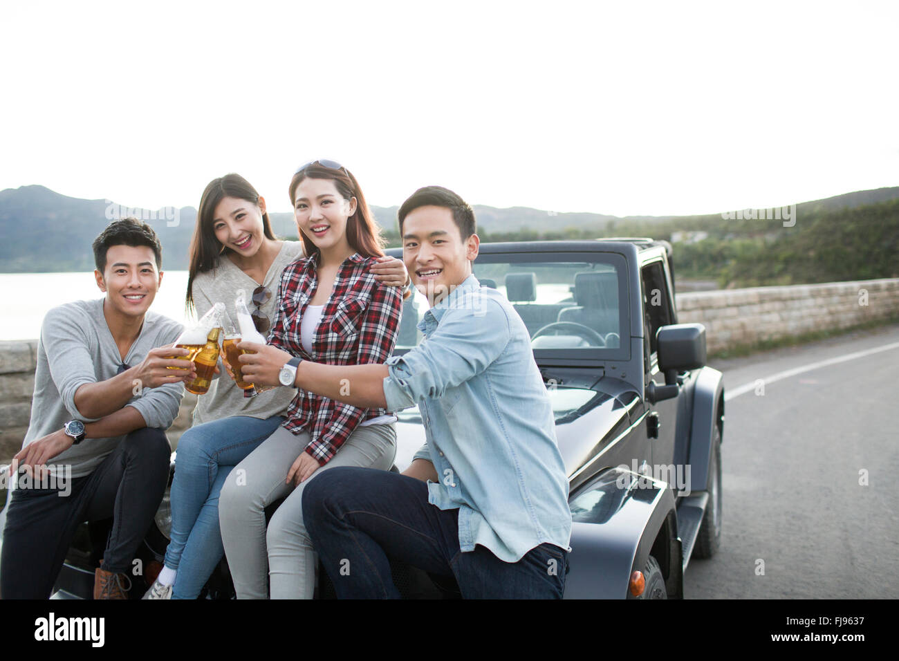 Happy Chinese friends drinking beer on a jeep Stock Photo - Alamy