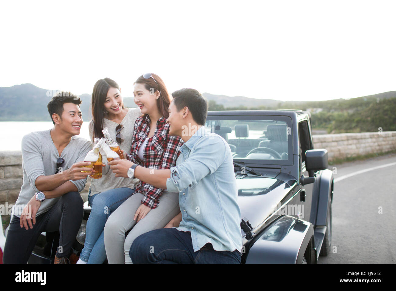 Happy Chinese friends drinking beer on a jeep Stock Photo - Alamy