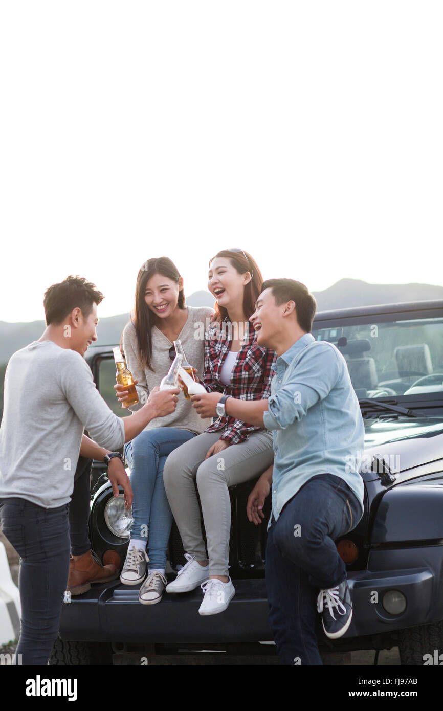 Happy Chinese friends drinking beer on a jeep Stock Photo - Alamy