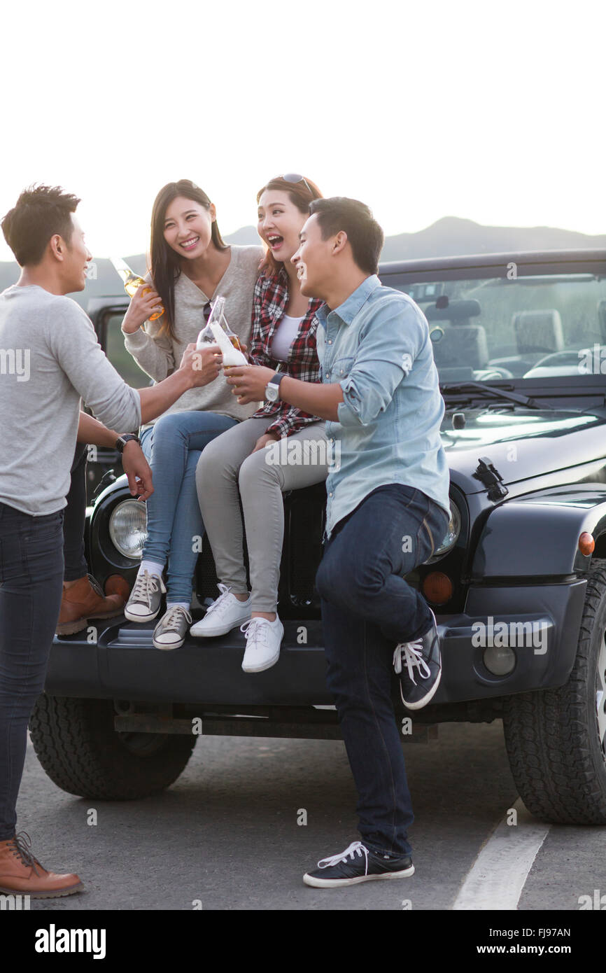 Happy Chinese friends drinking beer on a jeep Stock Photo - Alamy