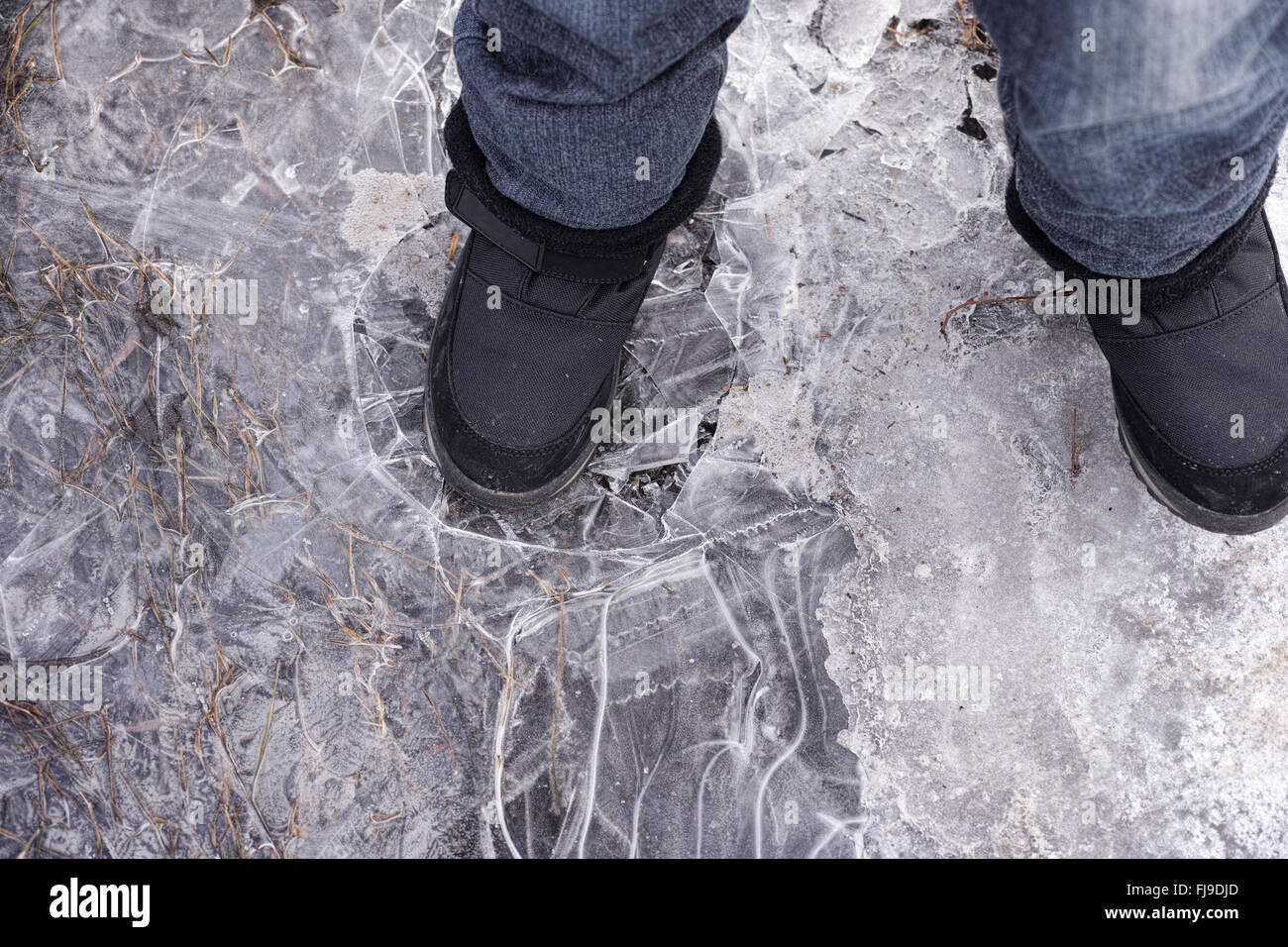 Child steps on frozen puddle with thin ice Stock Photo - Alamy