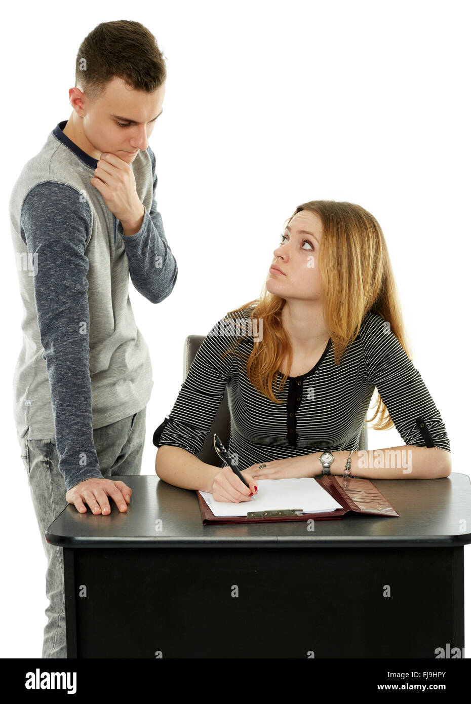 Two teenagers classmates working together, the boy is helping the girl ...