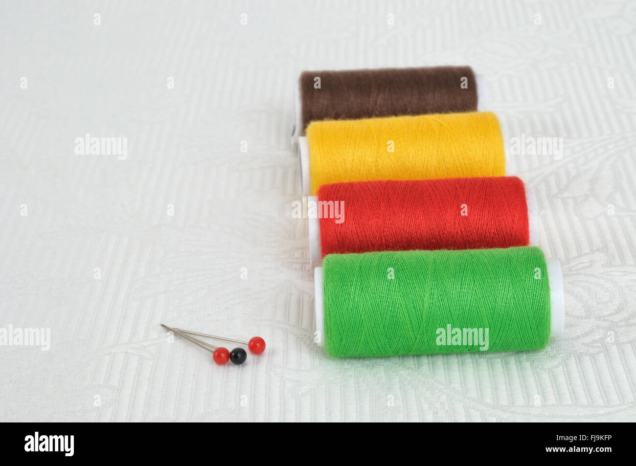 Spools of threads of different colors and needles on a light table ...