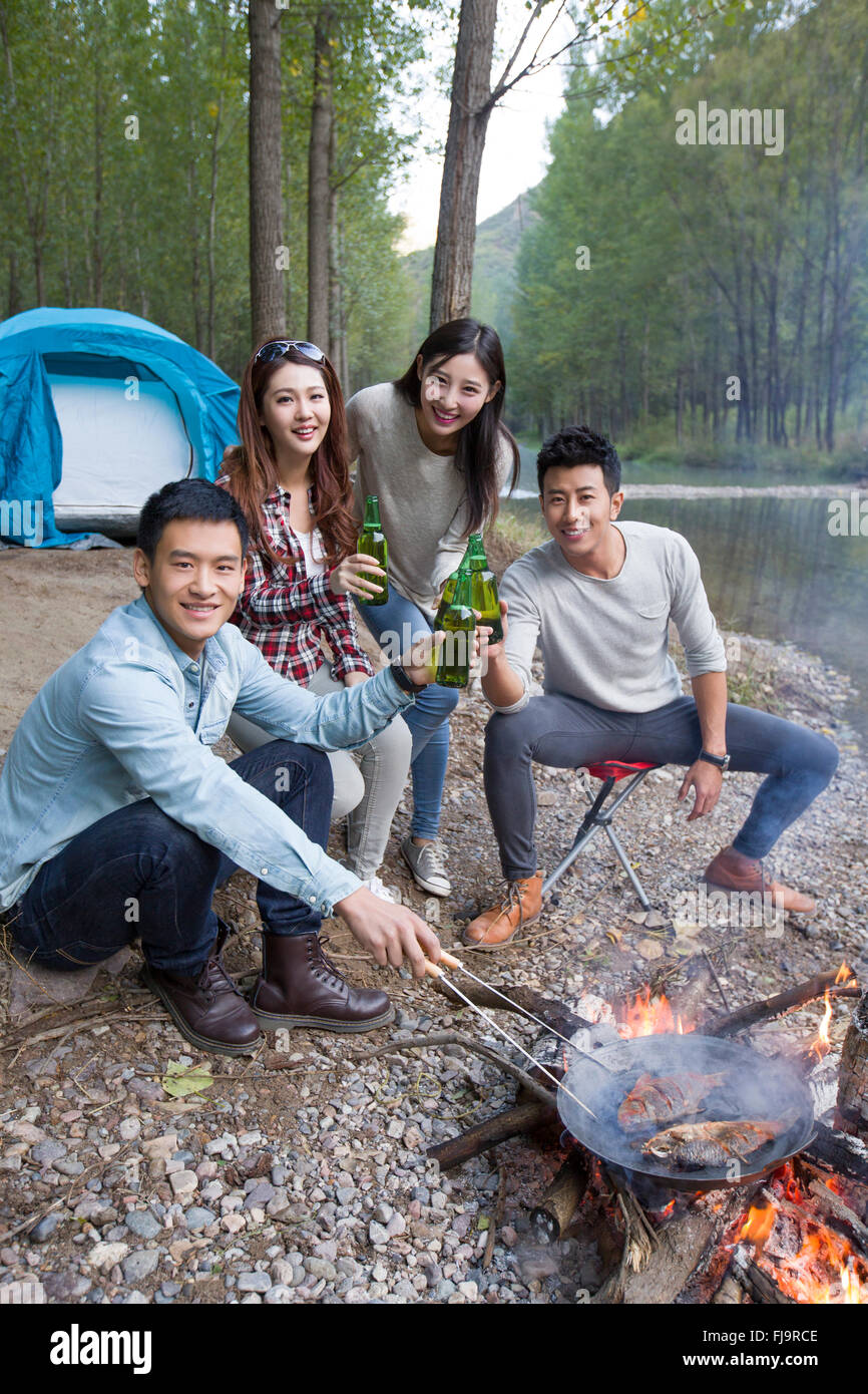 Young Chinese friends sitting around campfire drinking beer Stock Photo ...