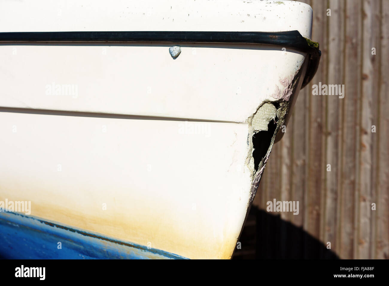 A damaged sailboat resting outside a building. A large hole is in the ...